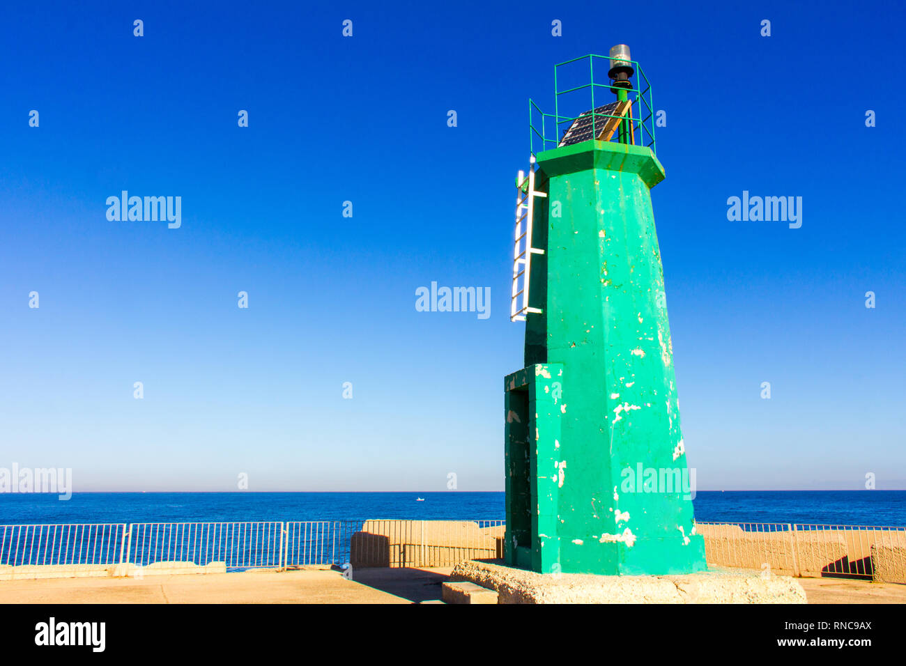 A green lighthouse in Denia, Spain. The blue sky is in the background ...