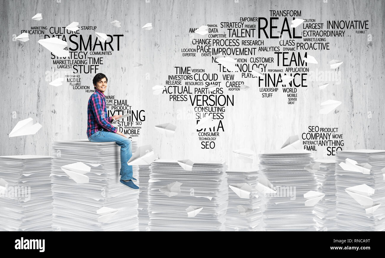 Attractive man sitting on pile of paper documents Stock Photo - Alamy