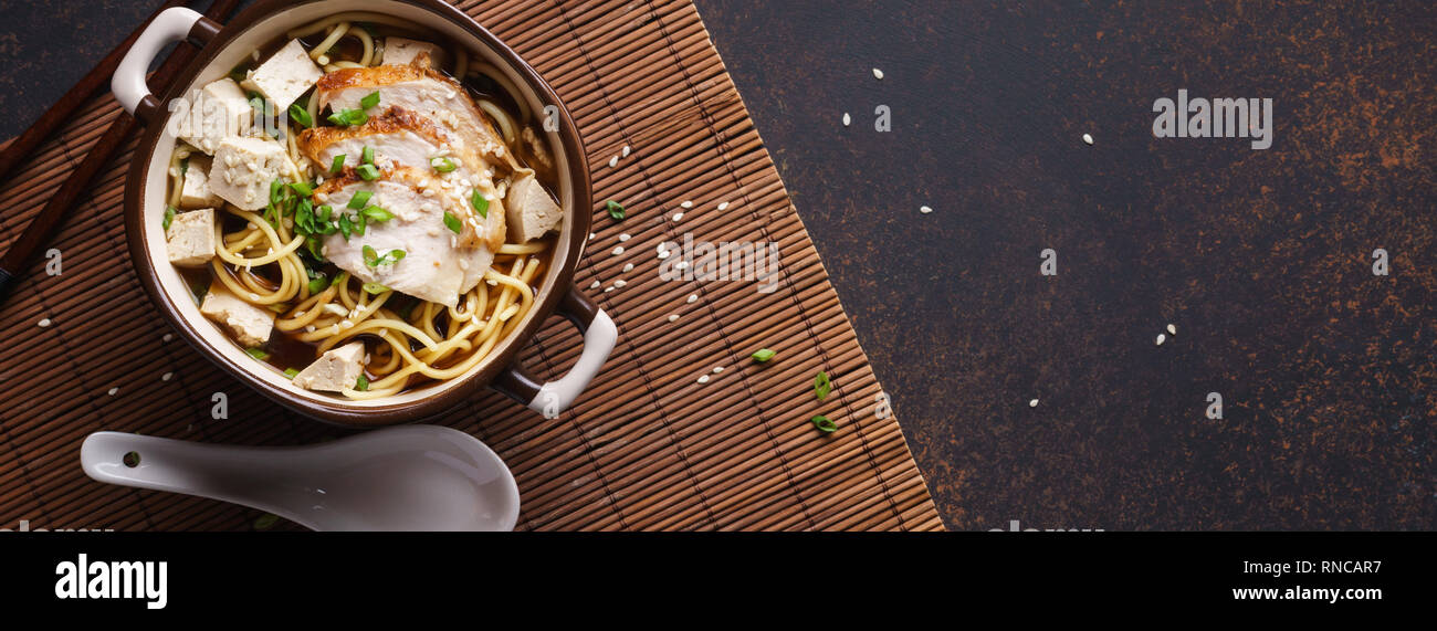 Asian miso ramen noodles with chicken and tofu. Dark background. Long ...