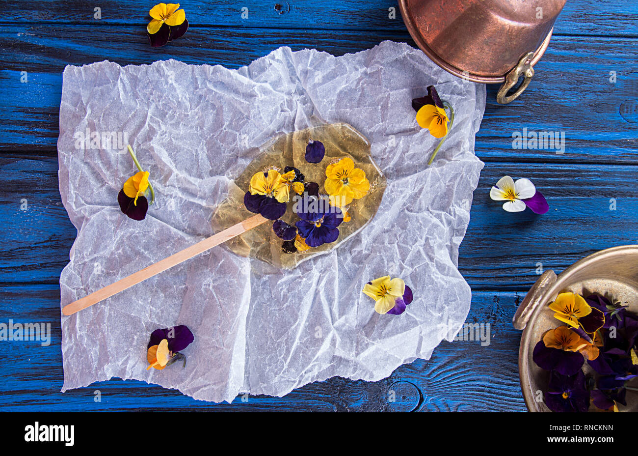 Beautiful lollipop caramel with edible violet flowers on parchment ...