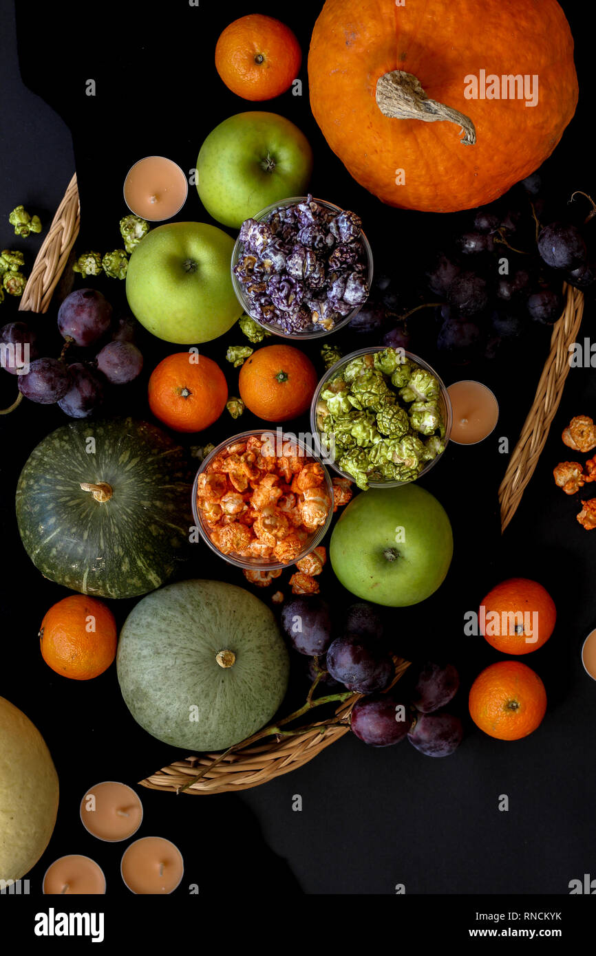 Green, purple and orange colored popcorn and fruit mix on a dark ...