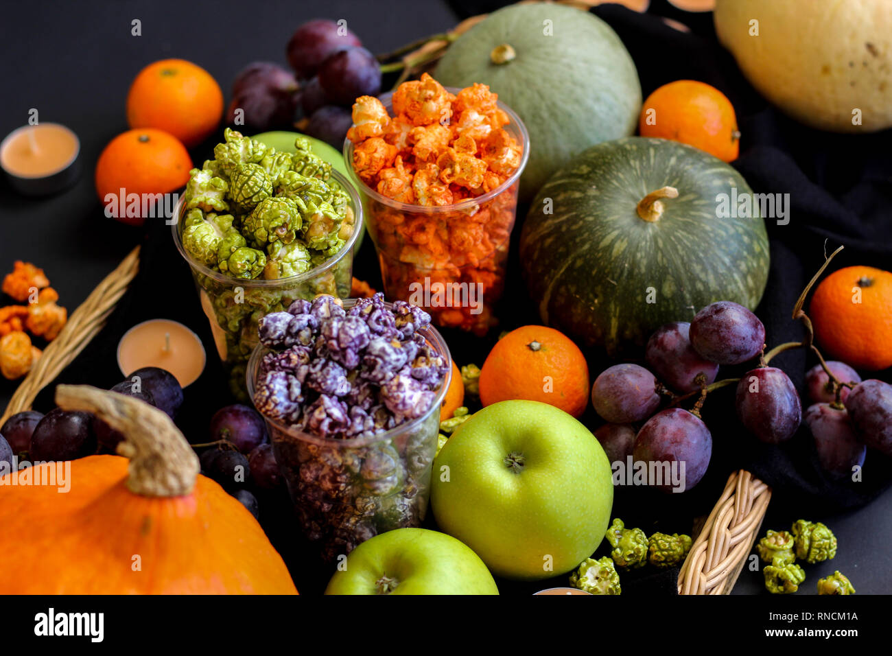 Green, purple and orange colored popcorn and fruit mix on a dark ...