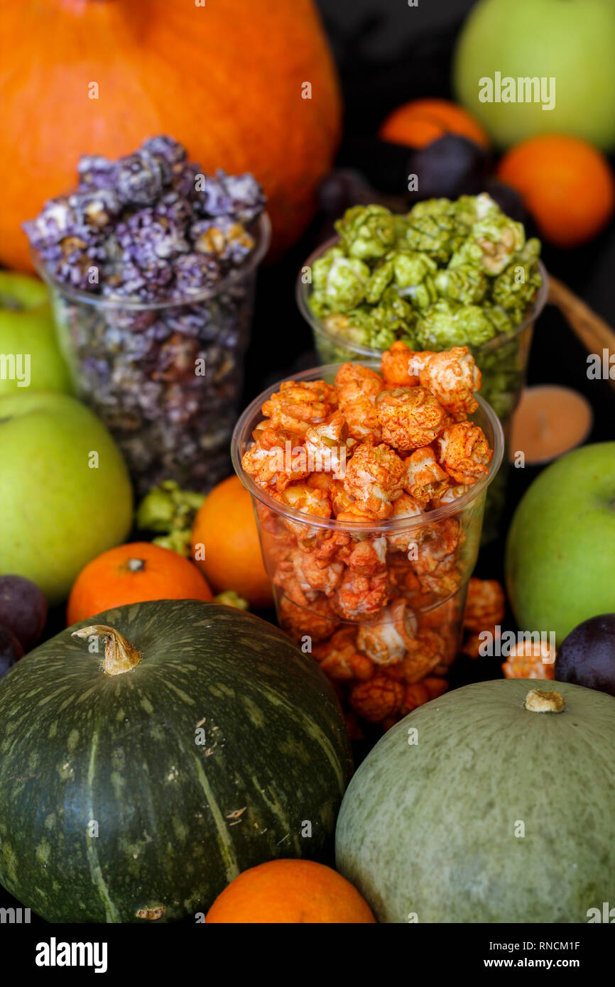 Green, purple and orange colored popcorn and fruit mix on a dark ...