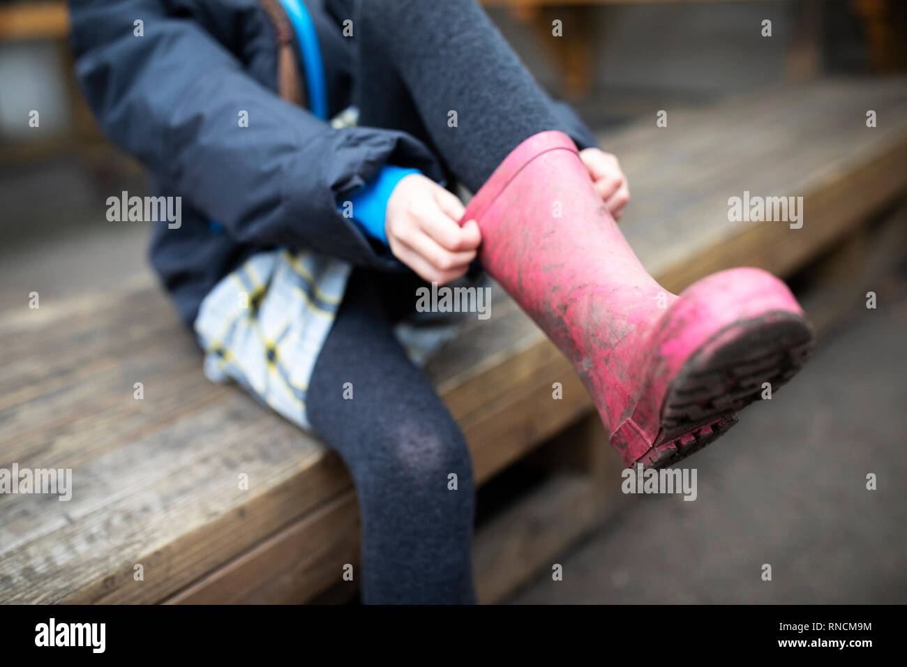 Primary school aged girl pulling on pink wellies Stock Photo - Alamy