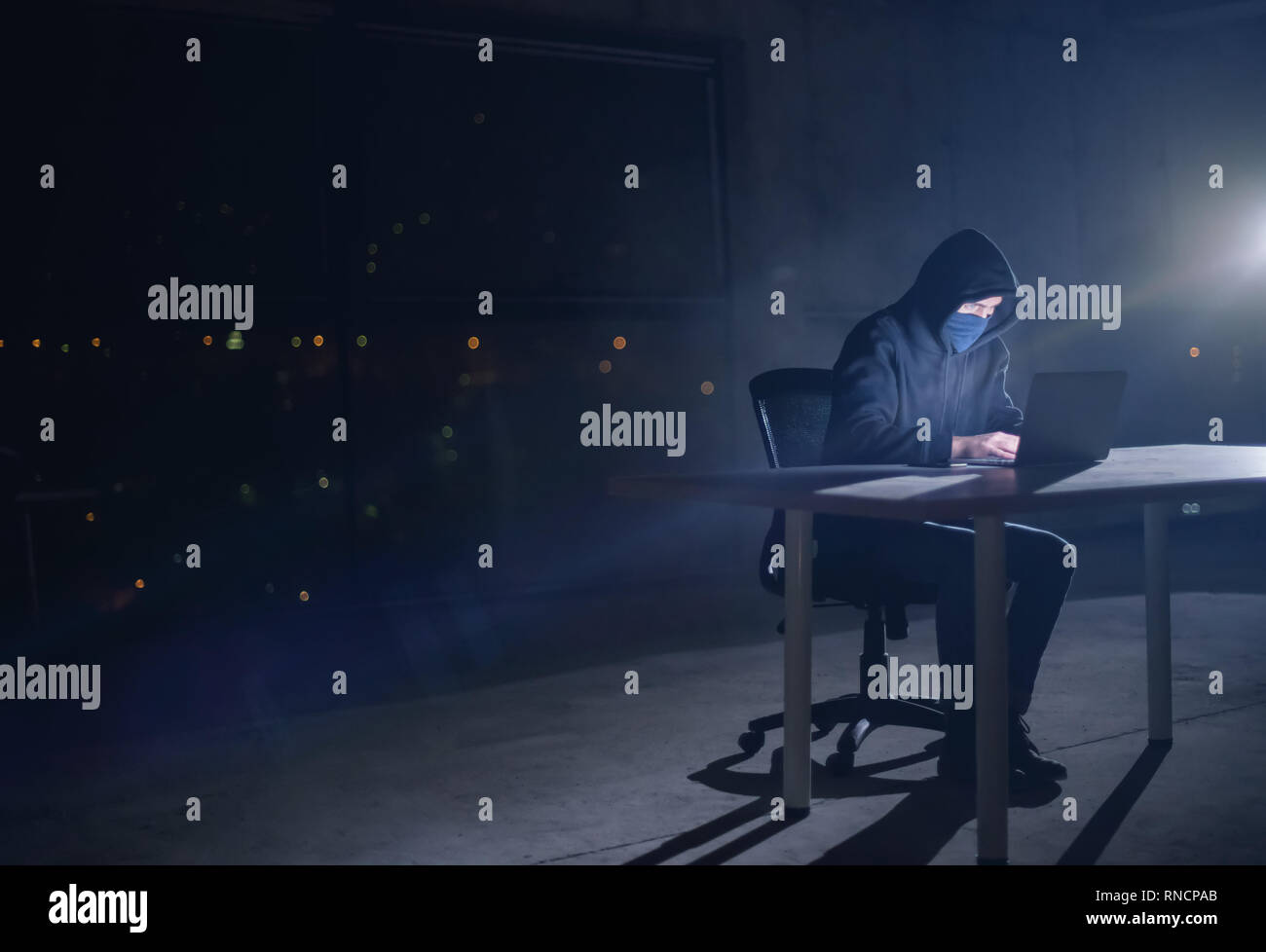 Young talented hacker using laptop computer while working in dark ...