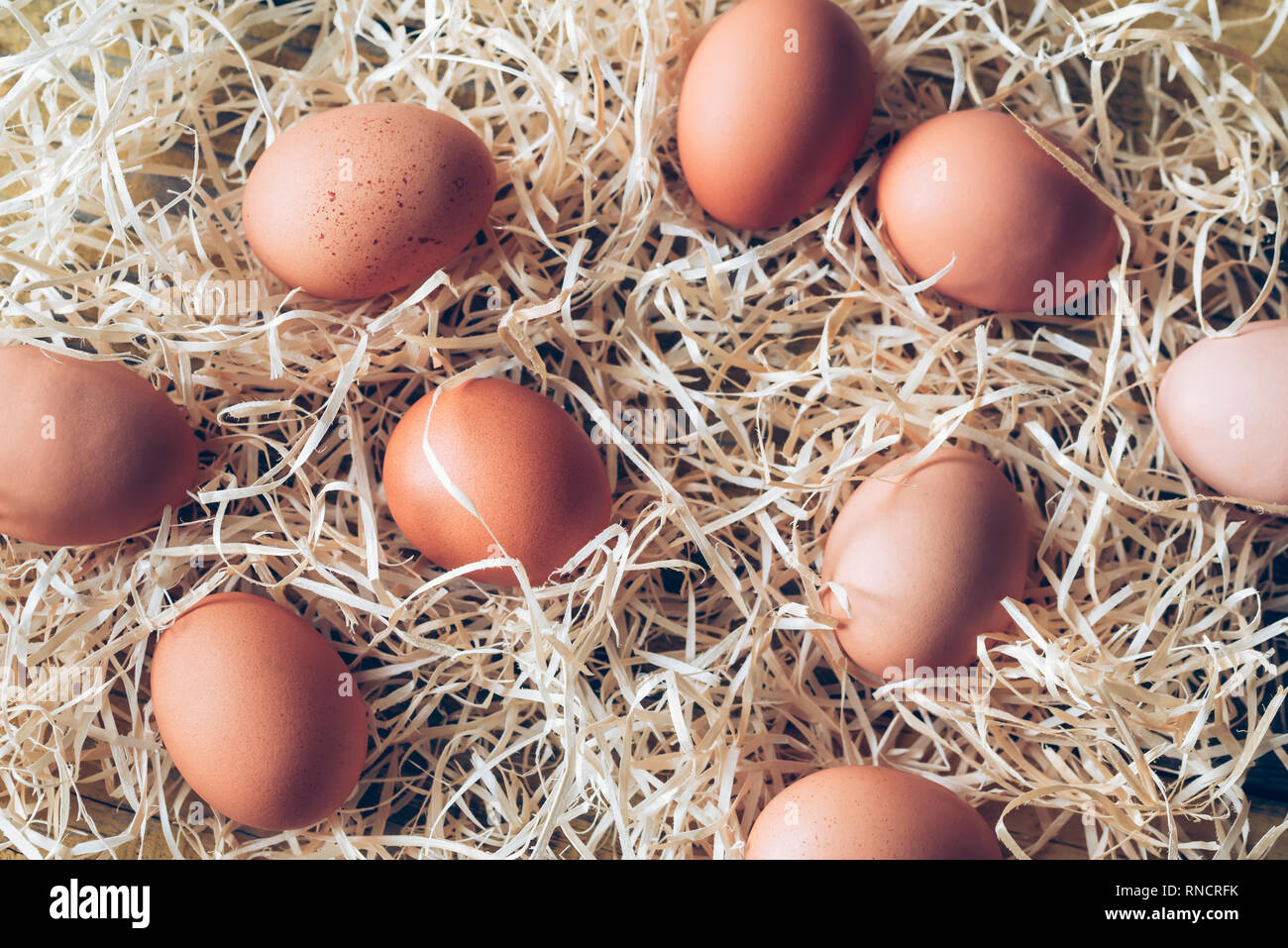 Raw chicken eggs in the hay: top view Stock Photo - Alamy