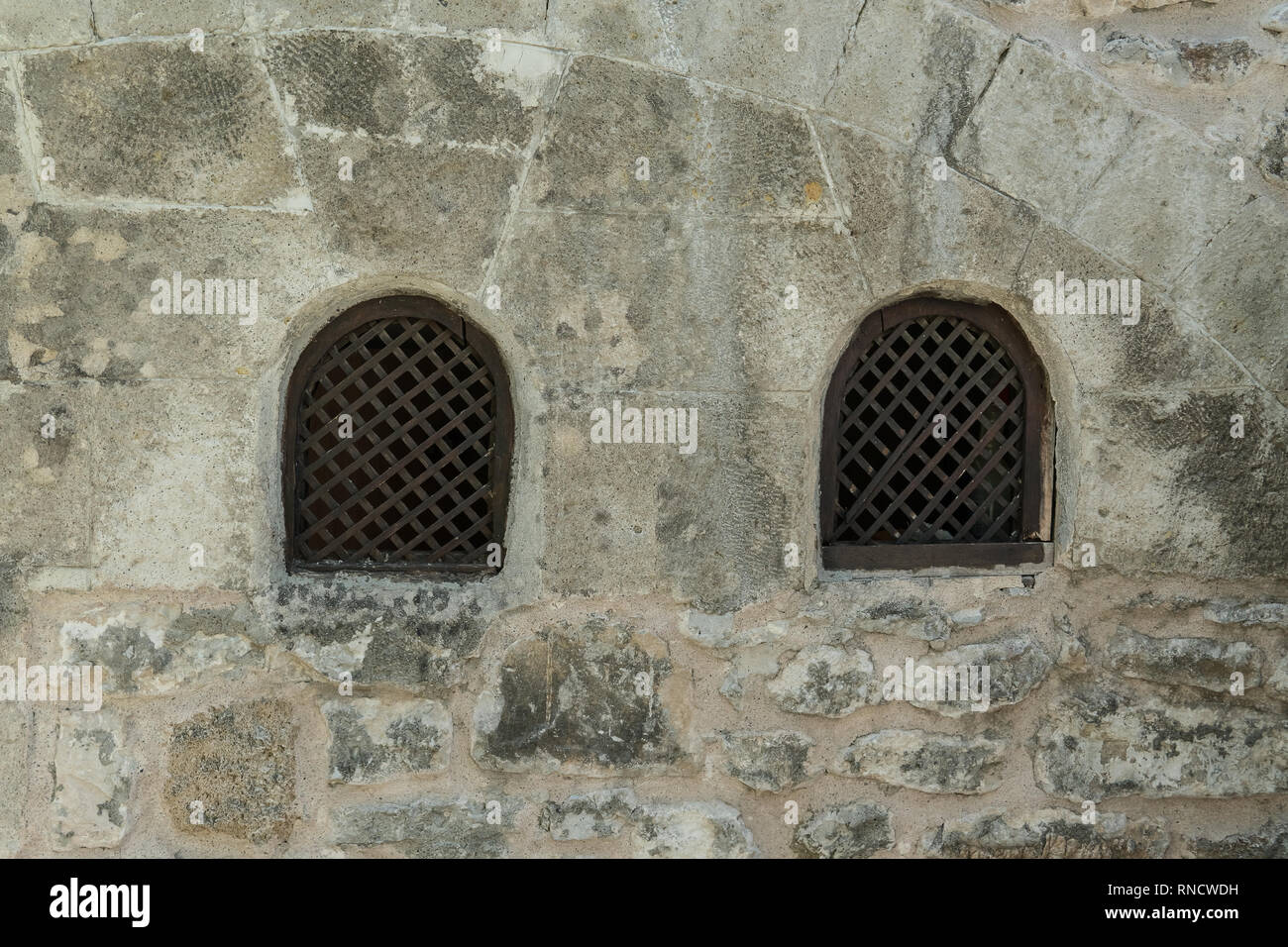 Old stone brick wall, two windows with bars. Grunge building material ...
