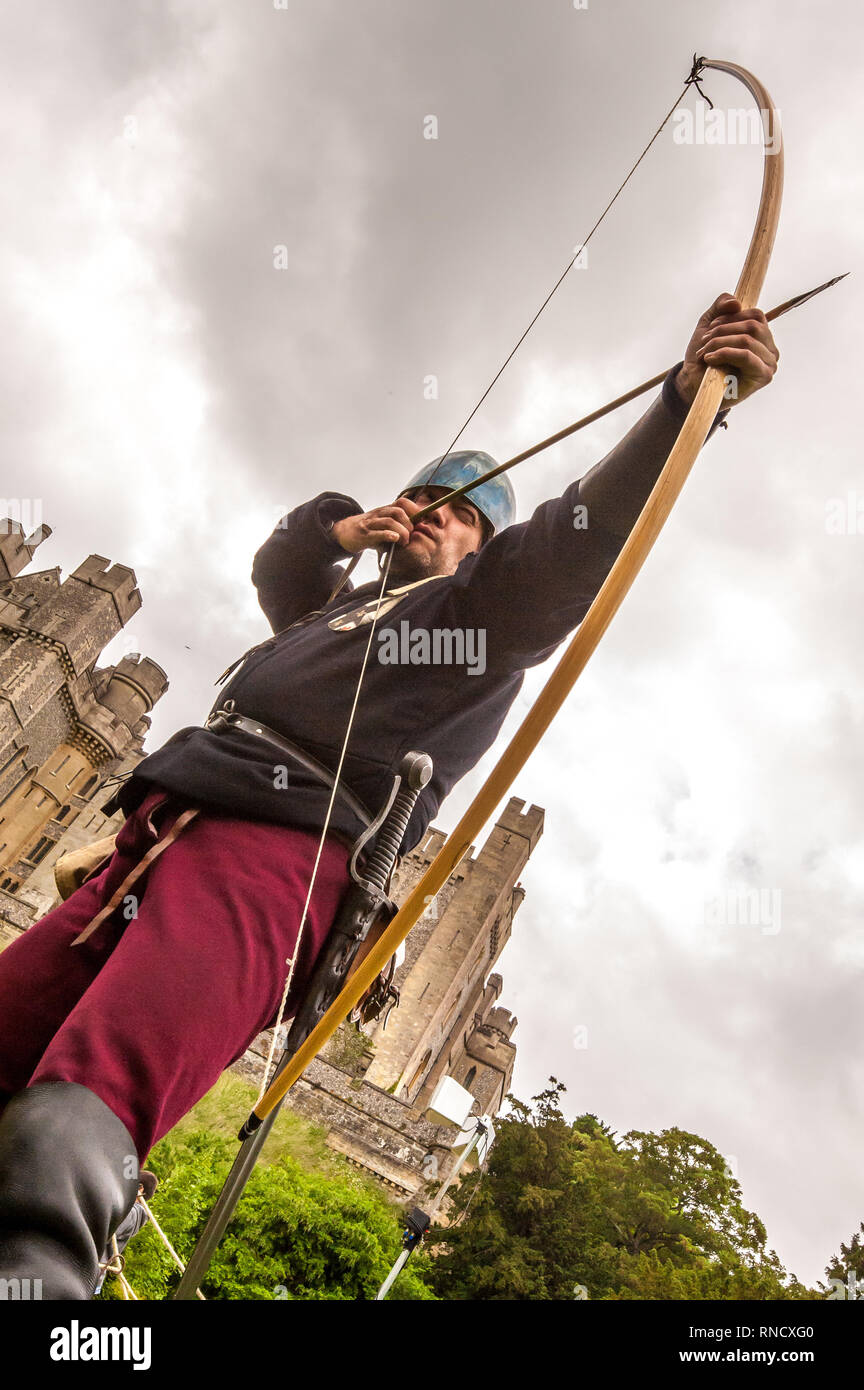 An archer in mediaeval dress sights along his bow during a historical ...
