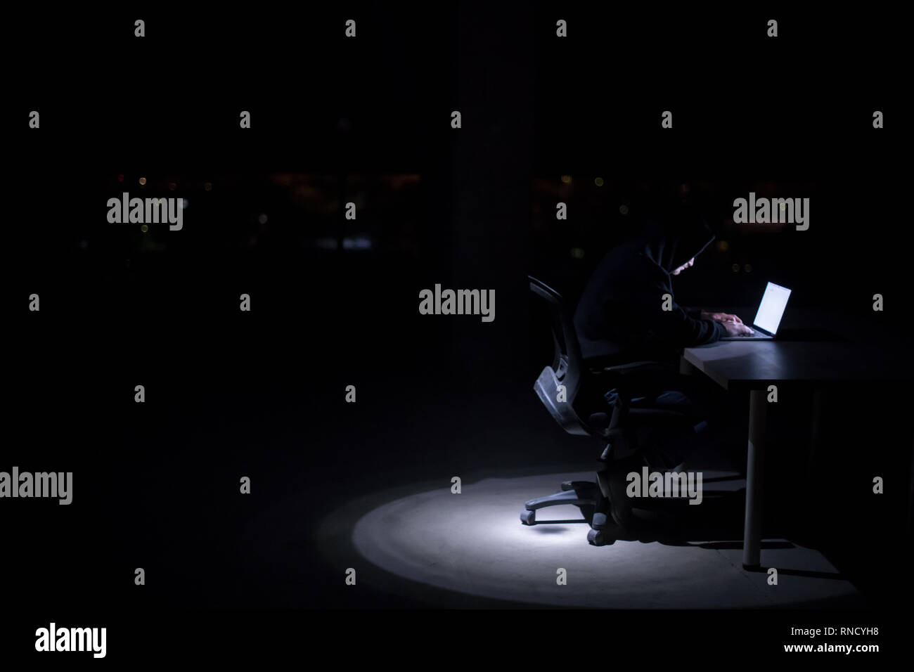 Young talented hacker using laptop computer while working in dark ...