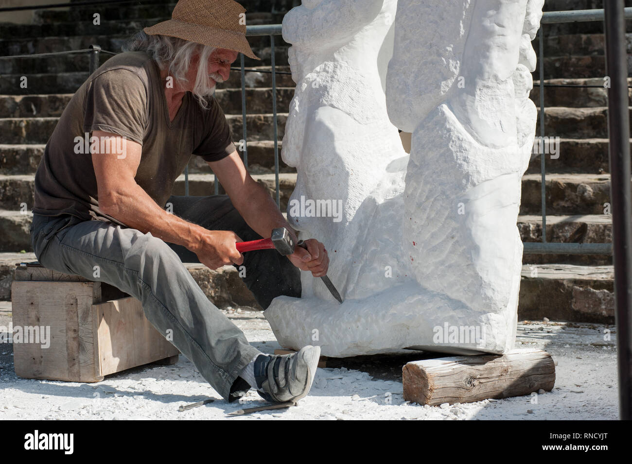 Senior sculptor working outdoor at the marble sculpture in his workshop ...