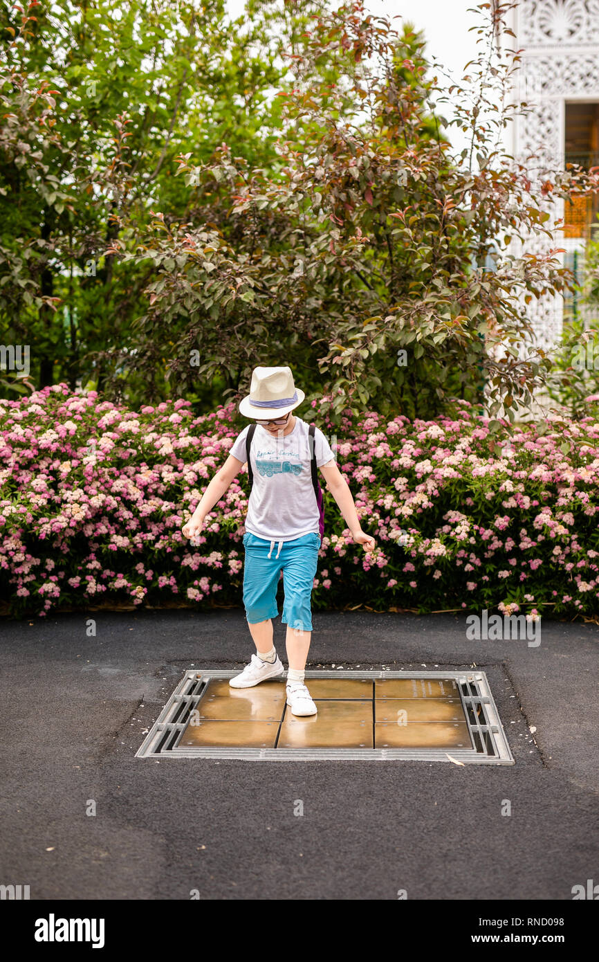 Blonde boy in the hat and big glasses in playground in the park with ...