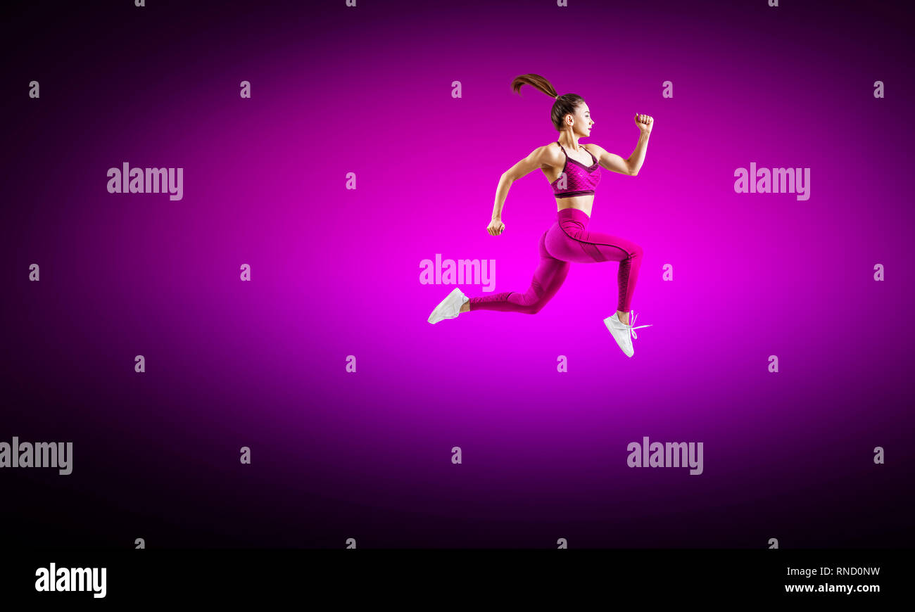 Young woman runner in purple sportswear jump in the air Stock Photo - Alamy