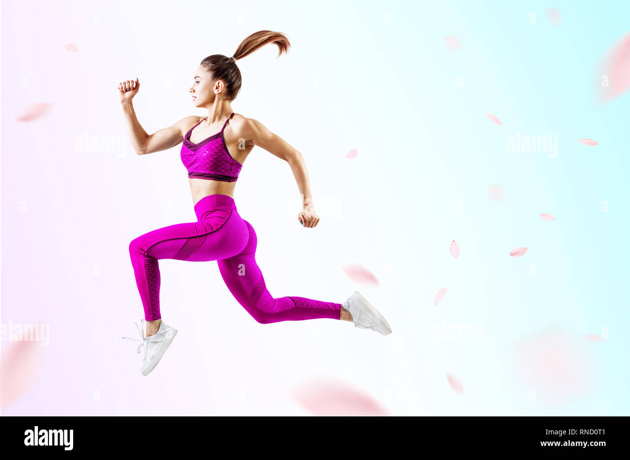 Young woman runner in purple sportswear jump in the air Stock Photo - Alamy