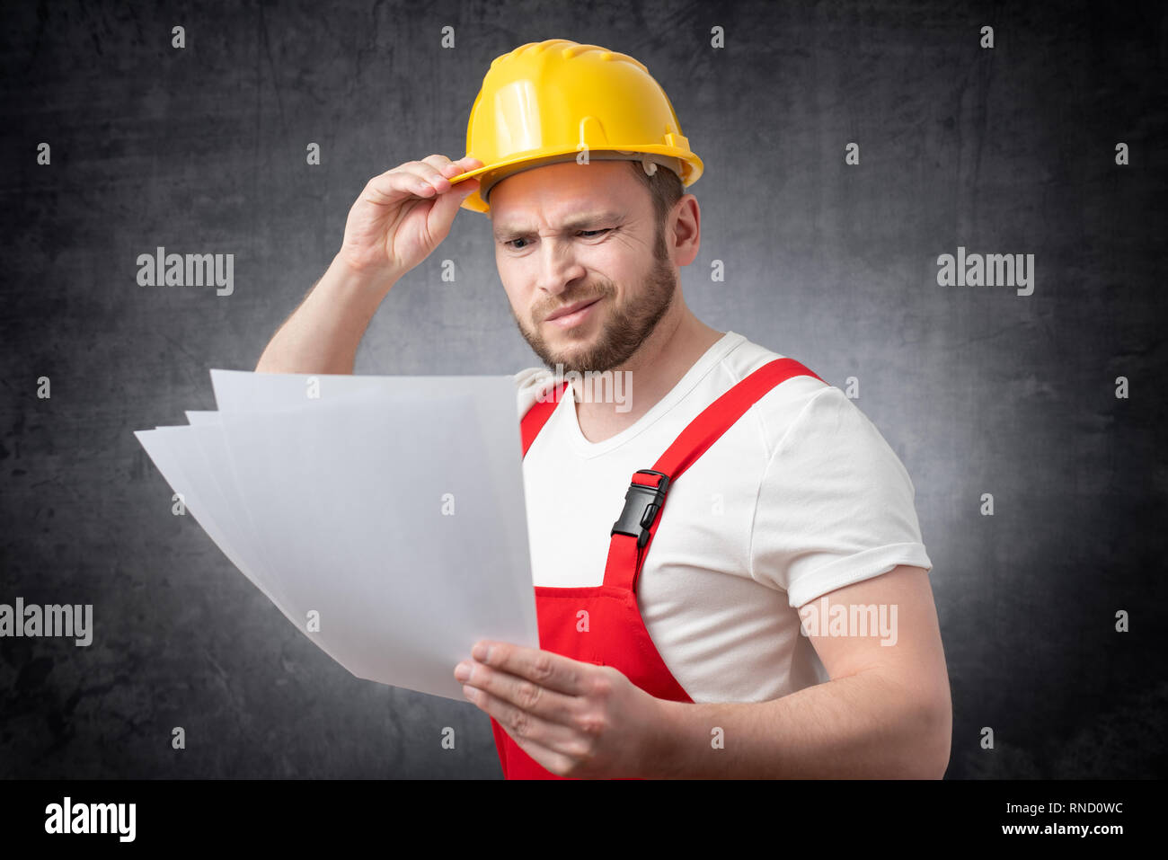 Confused construction worker holding papers Stock Photo - Alamy