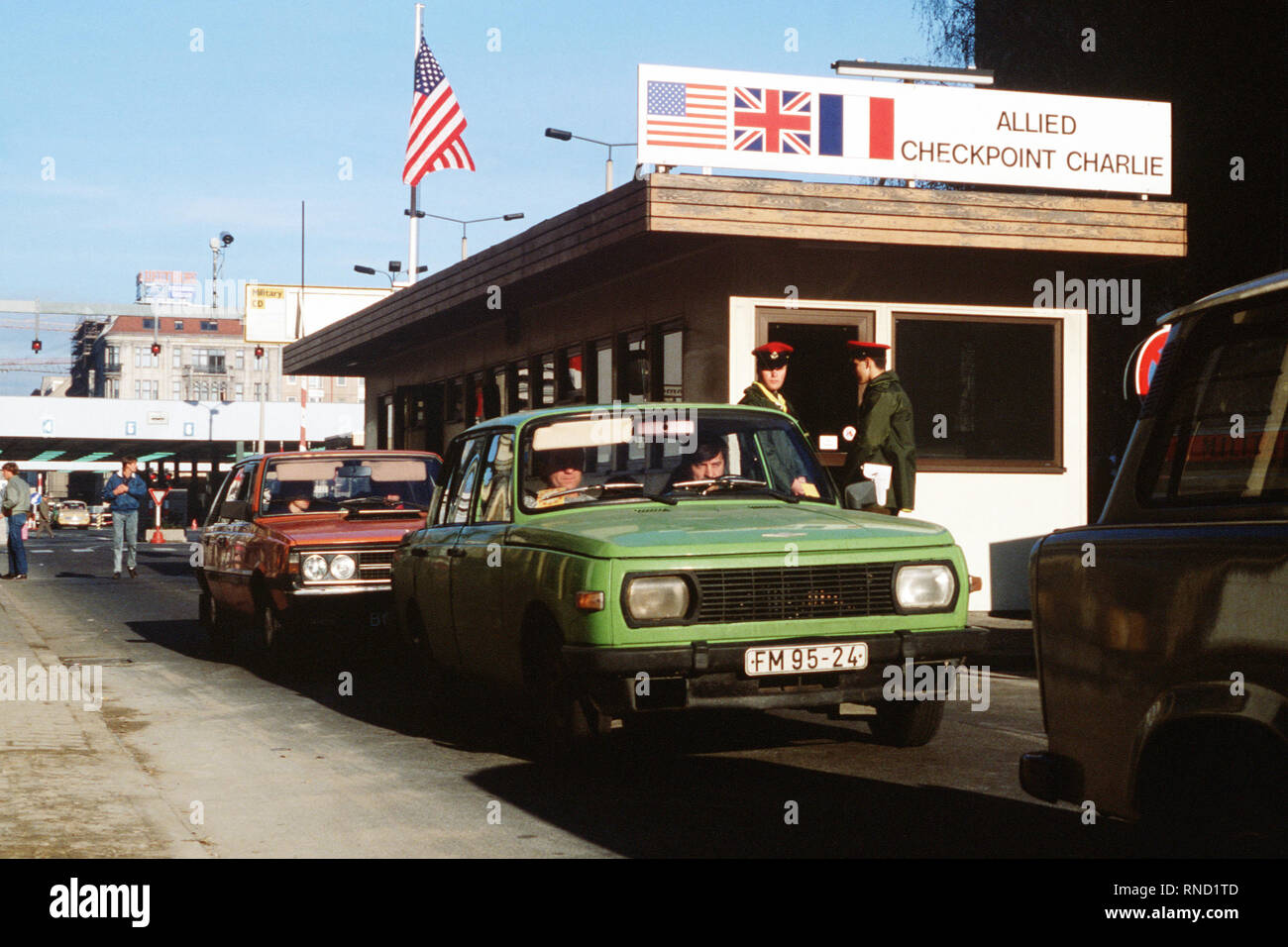 East Germans drive their vehicles through Checkpoint Charlie as they ...
