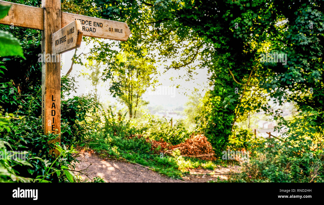 A typical wooden sign post showing local directions on a public pathway ...
