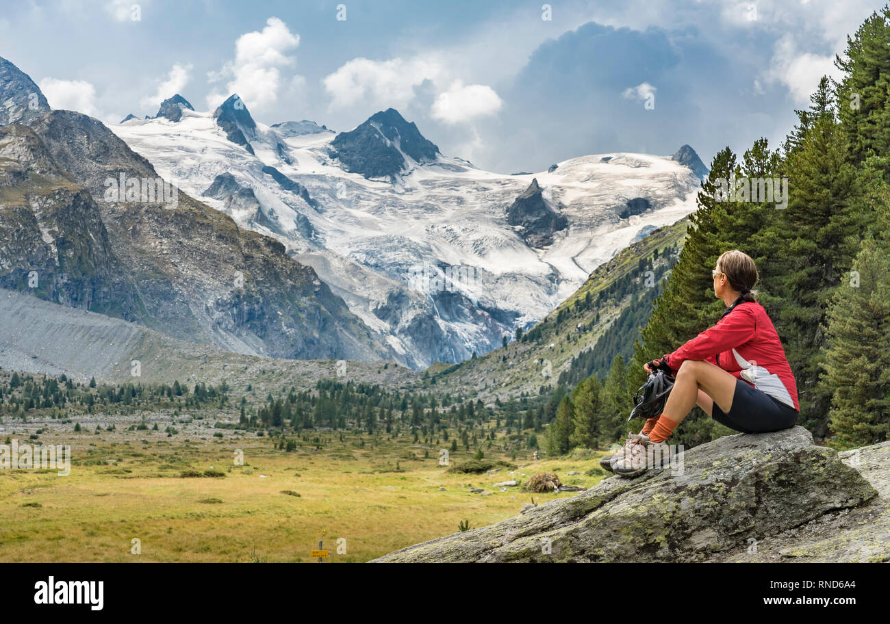 active senior woman, riding her e-mountain bike in the Roseg valley ...