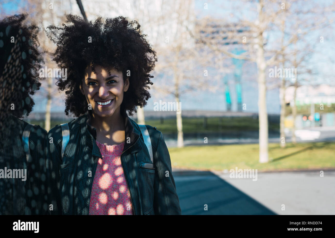 Portrait of black Woman with afro hair leaning on a wall in the street ...