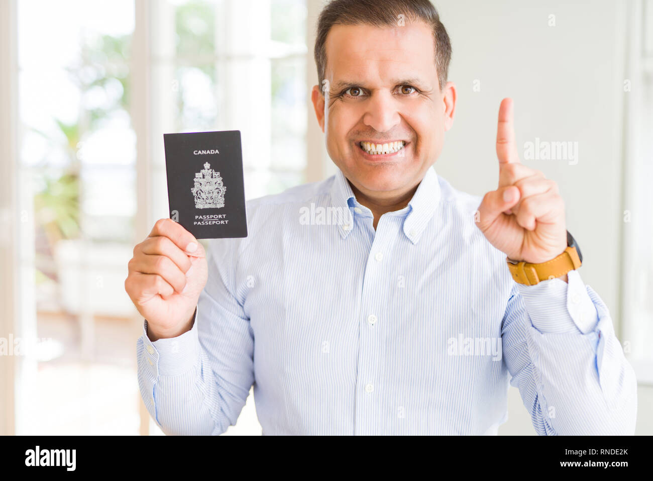 Middle age man holding holding Canadian passport surprised with an idea ...
