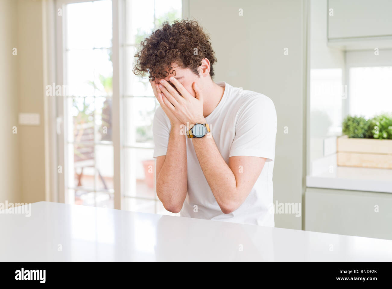 Young handsome man wearing white t-shirt at home with sad expression ...