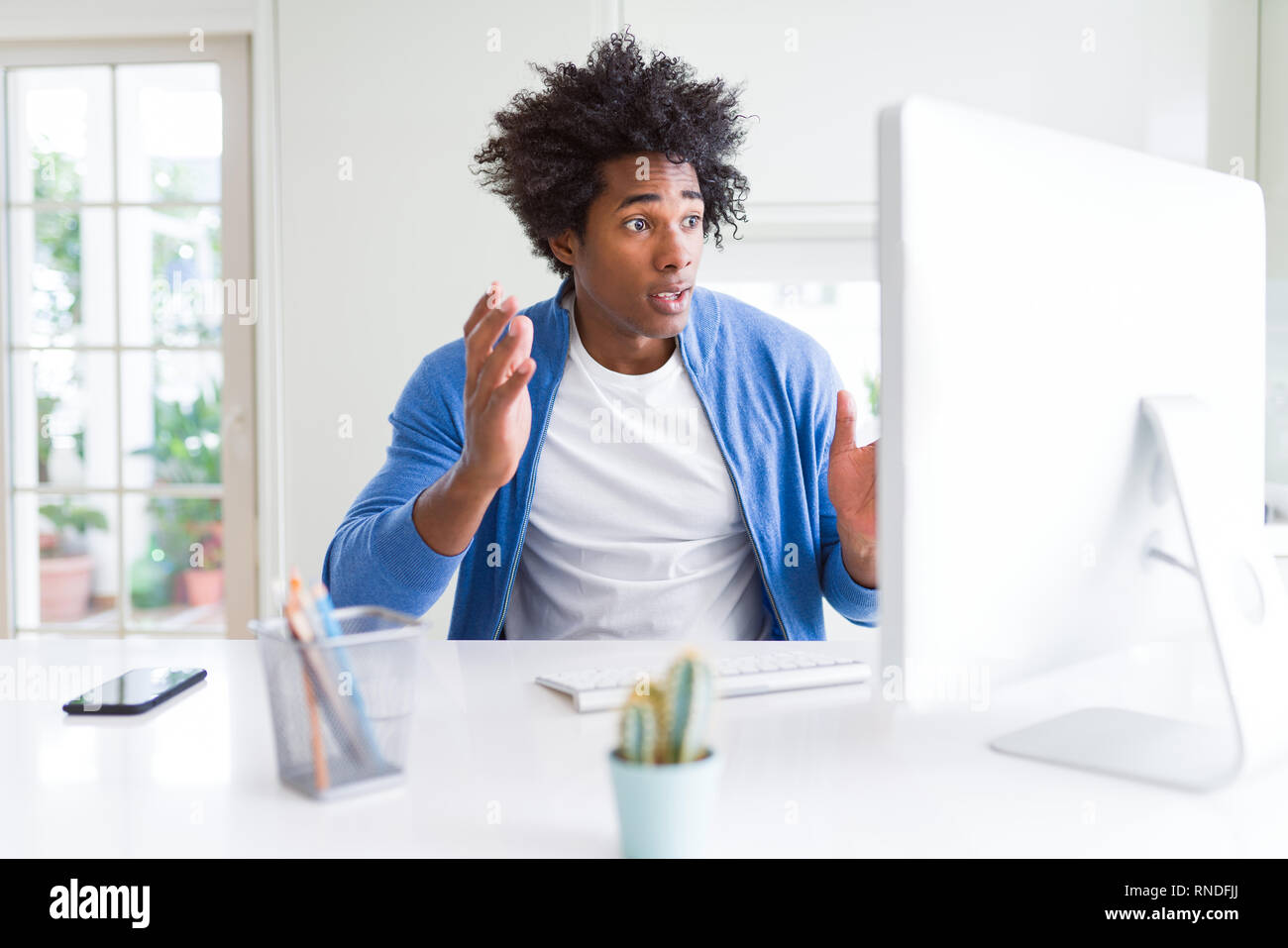 African American man working using computer scared in shock with a ...