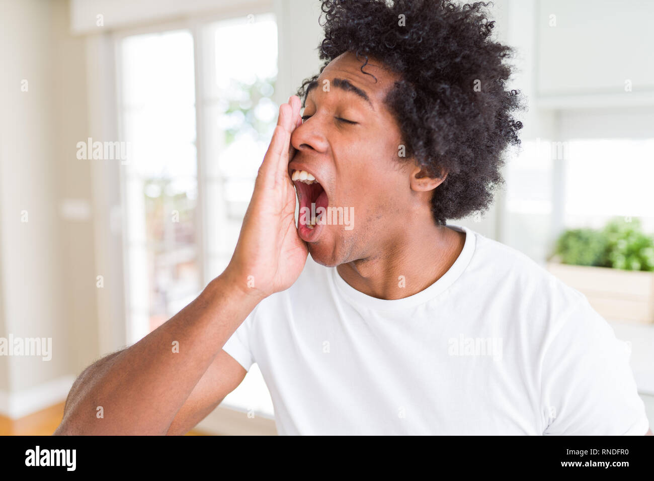 African American man wearing white t-shirt shouting and screaming loud ...