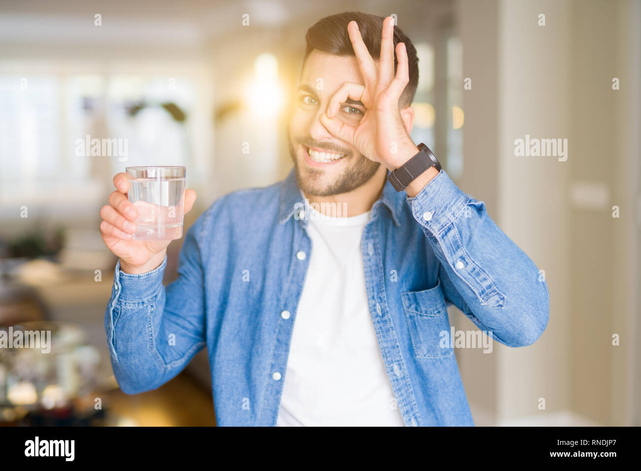 Young handsome man drinking a glass of water at home with happy face ...