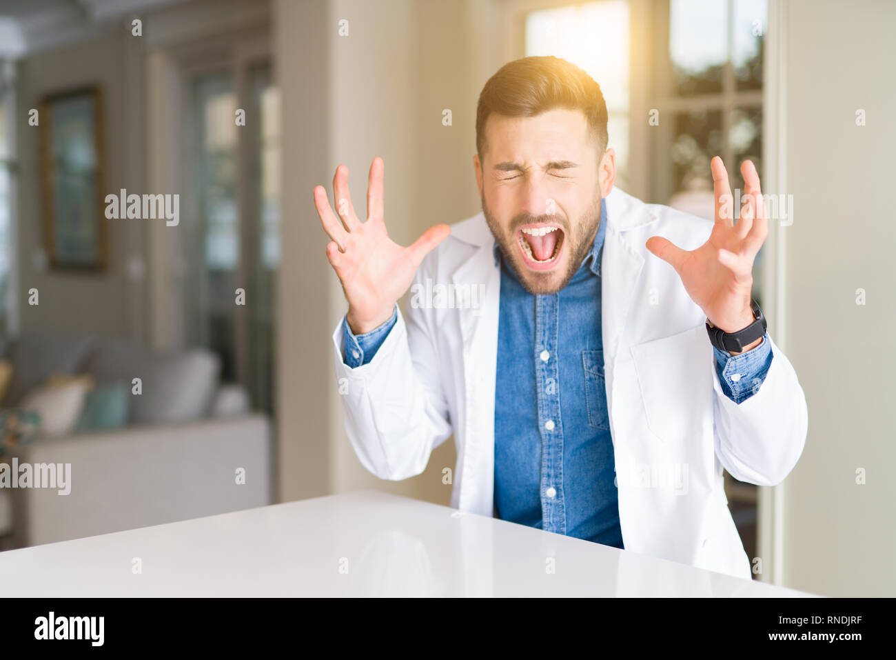 Young handsome doctor man at the clinic celebrating mad and crazy for ...