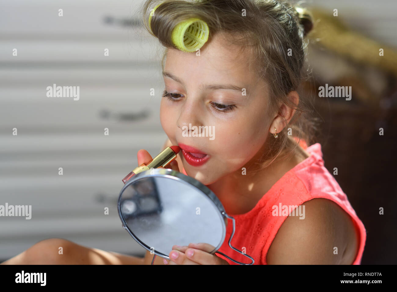 Child with nice cheeks smiles and paints lips indoors Stock Photo - Alamy
