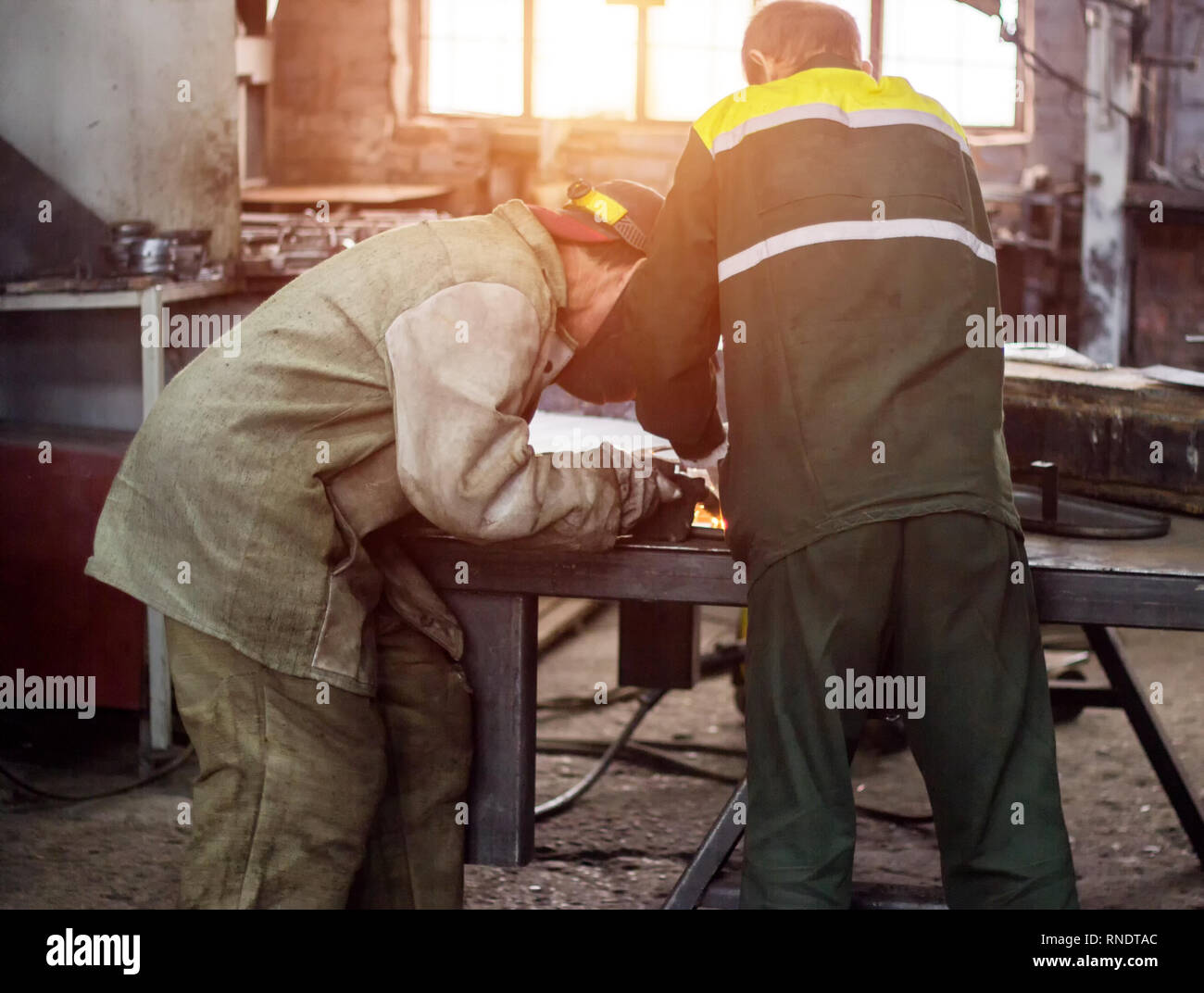 Two male workers at the factory welder and his assistant weld parts ...