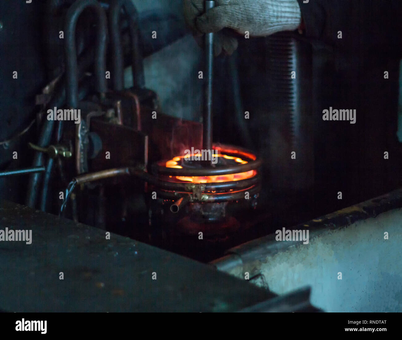 The worker makes hardening heat treatment of the metal gear on a ...