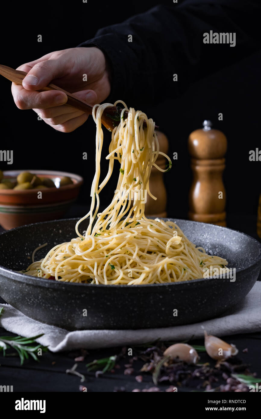 Serving traditional italian pasta from a pan. Male hands taking ...