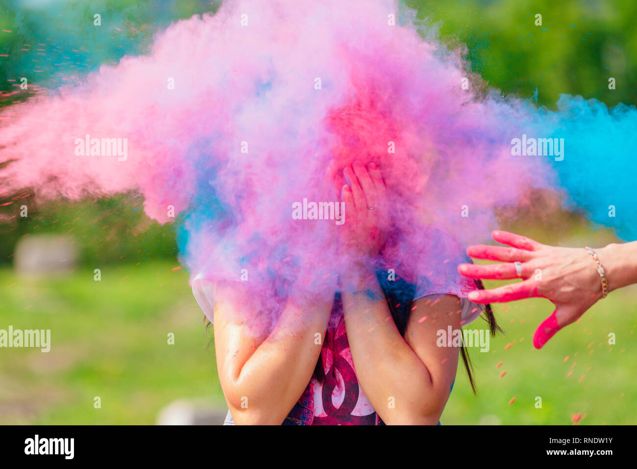 Woman stands in colorful splashes or clouds of holi powder outdoors ...