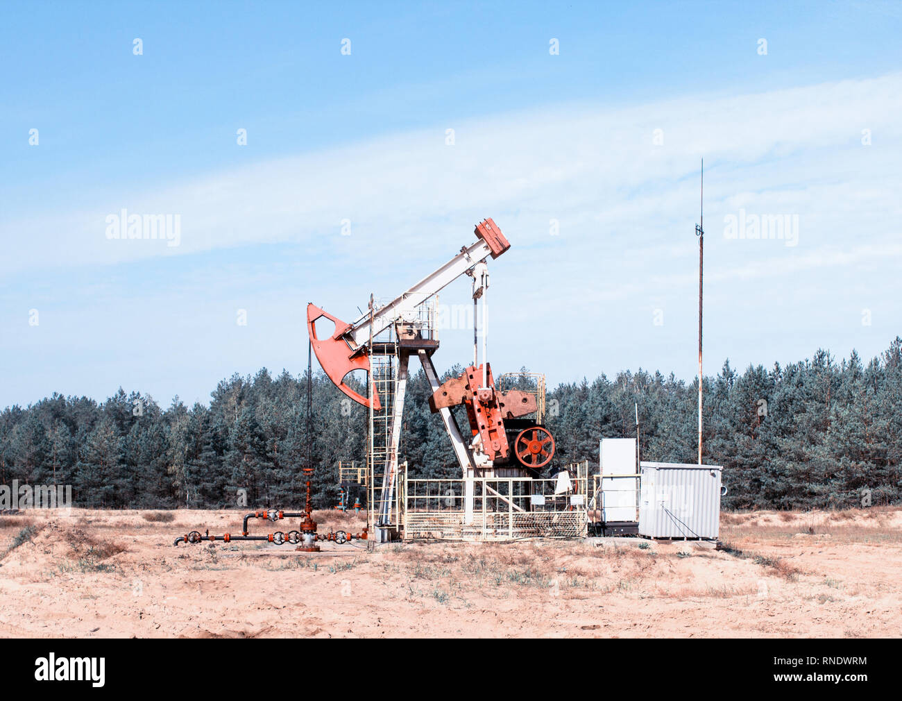 Oil production, oil well stands on the field among the forest, blue sky ...