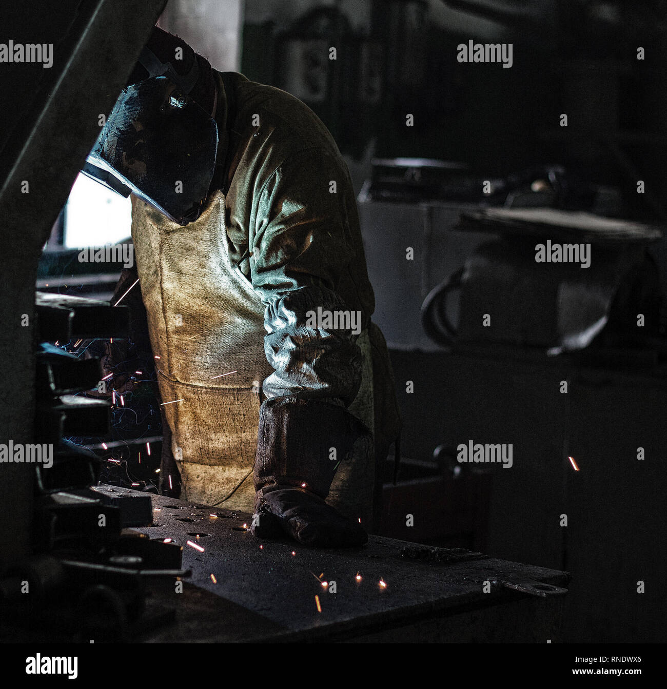 Welder at the factory welds metal parts, welding and sparks, dirty ...