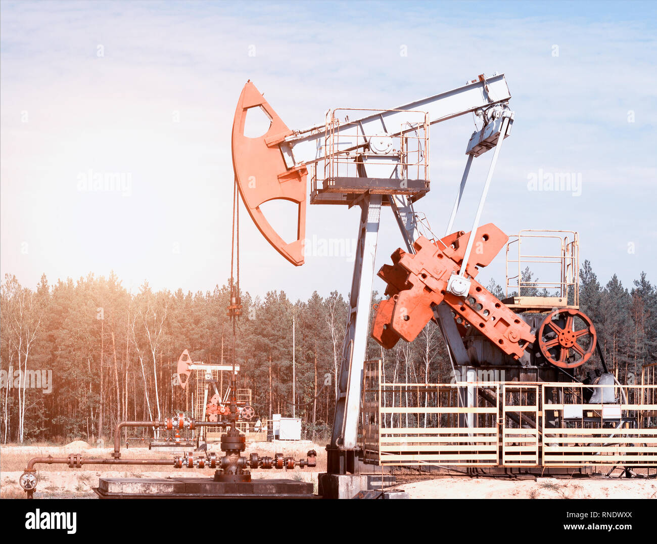 Oil production, oil well stands on the field among the forest, blue sky ...