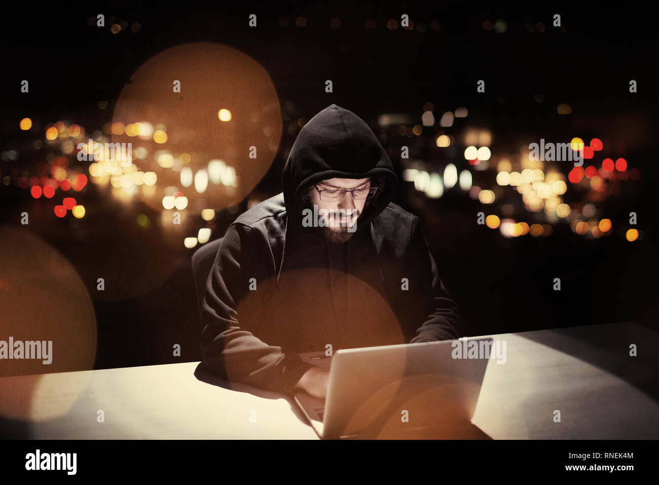 Young talented hacker using laptop computer while working in dark ...