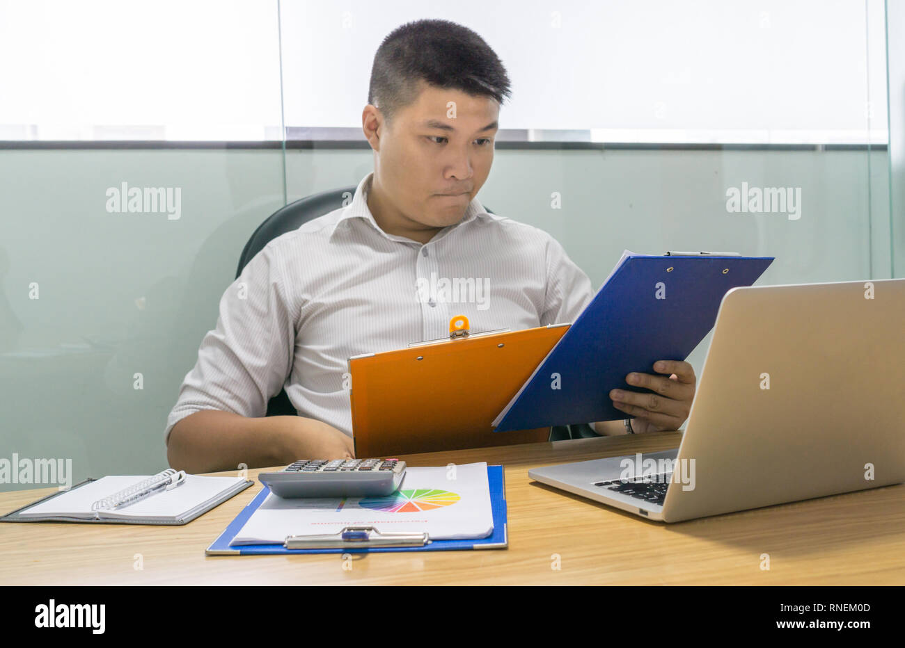 Young Asian businessman reading financial report document Stock Photo ...