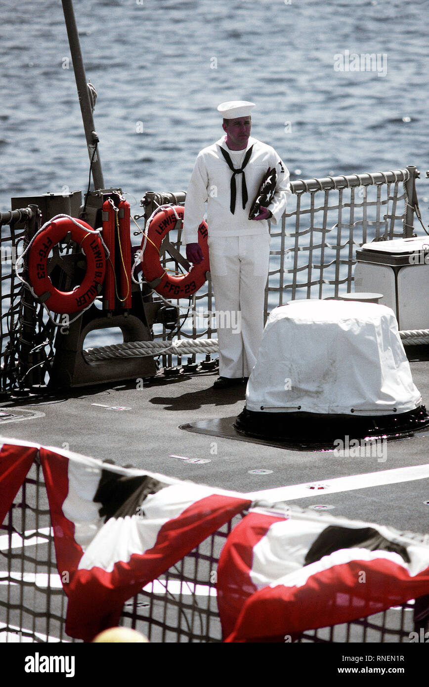 1982 - A crewman prepares to raise the flag during commissioning ...
