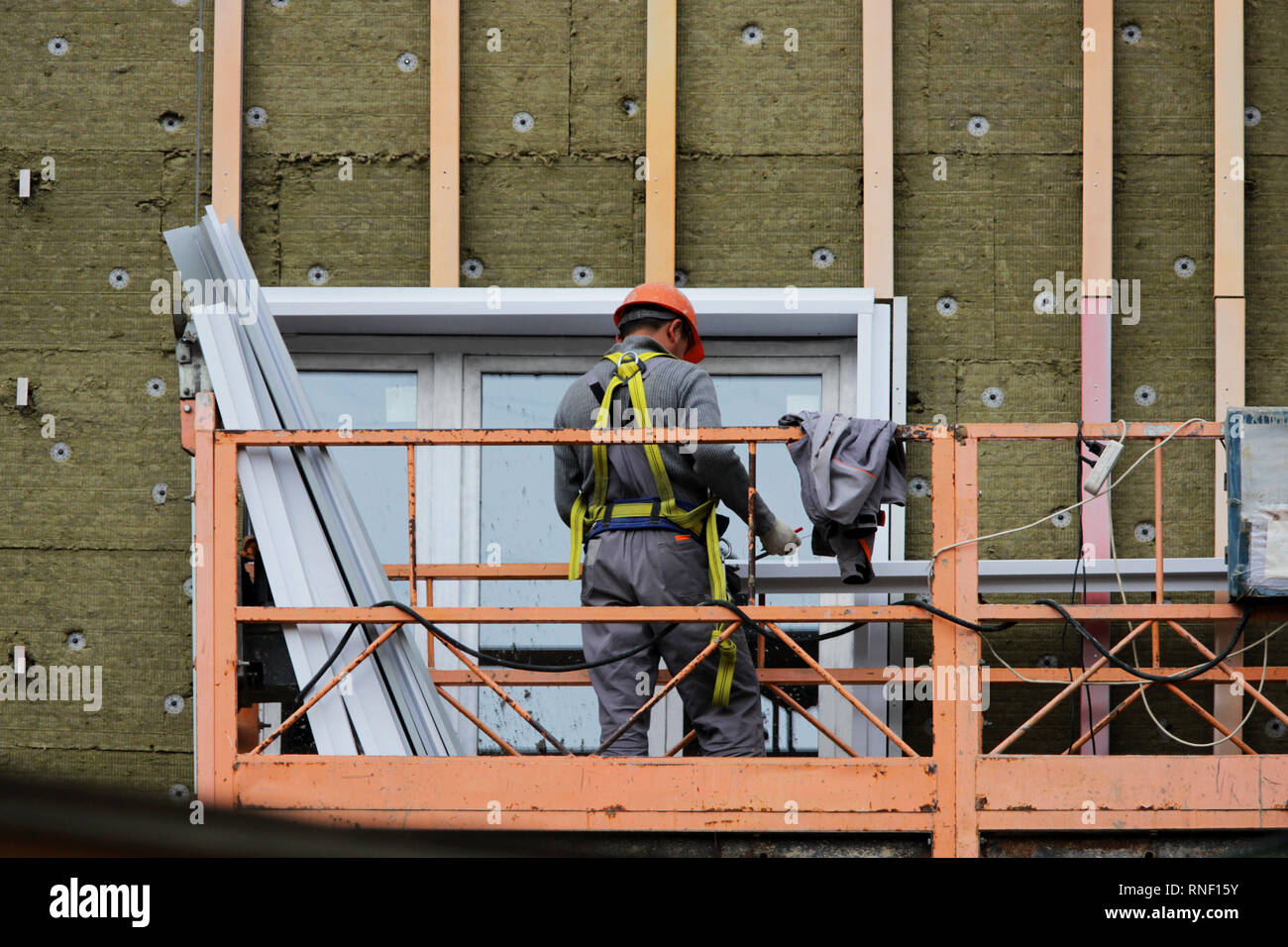 construction suspended orange cradle with worker on a newly built high ...