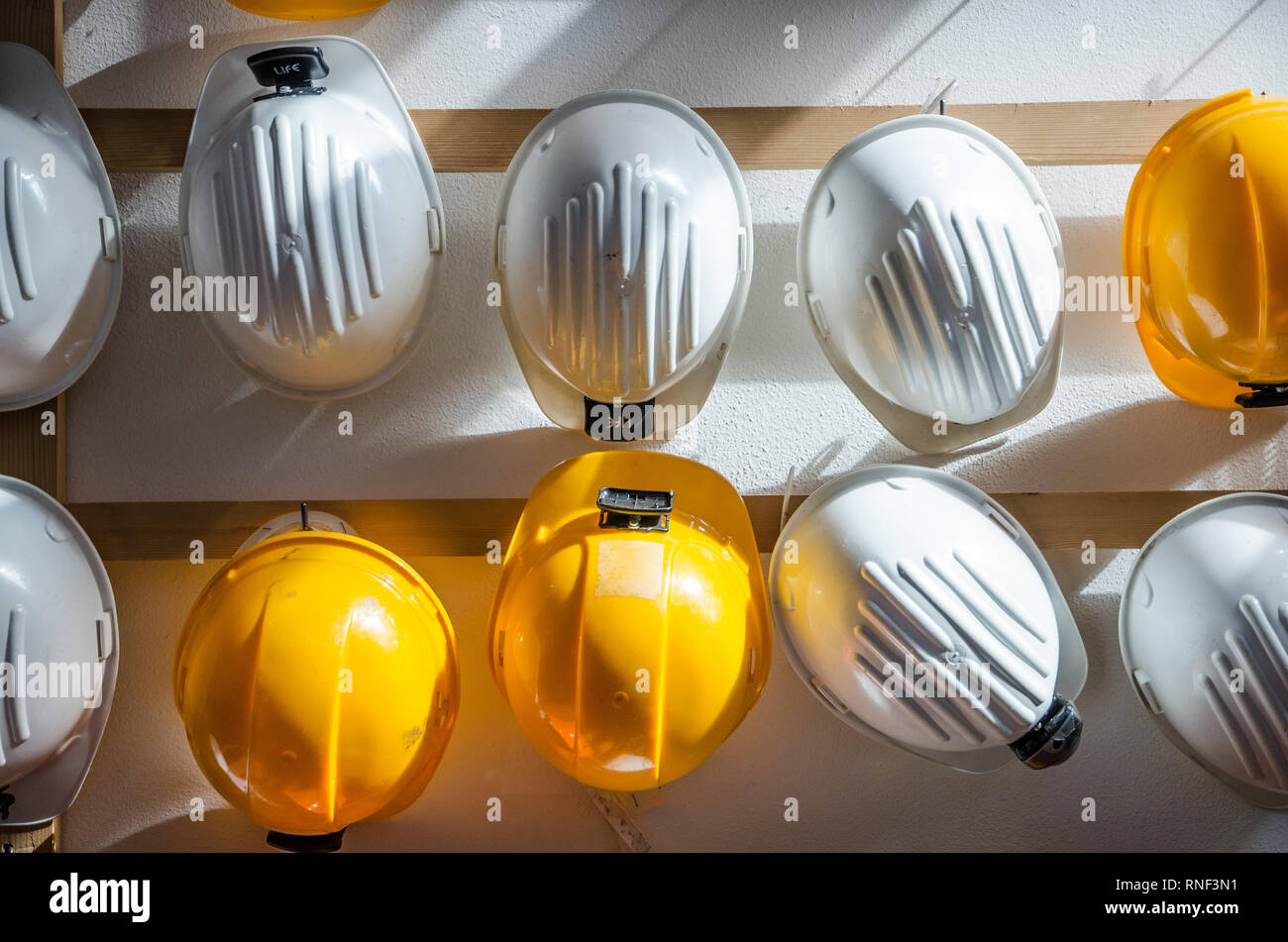 Racks with multicolored safety helmets for workers and miners Stock ...