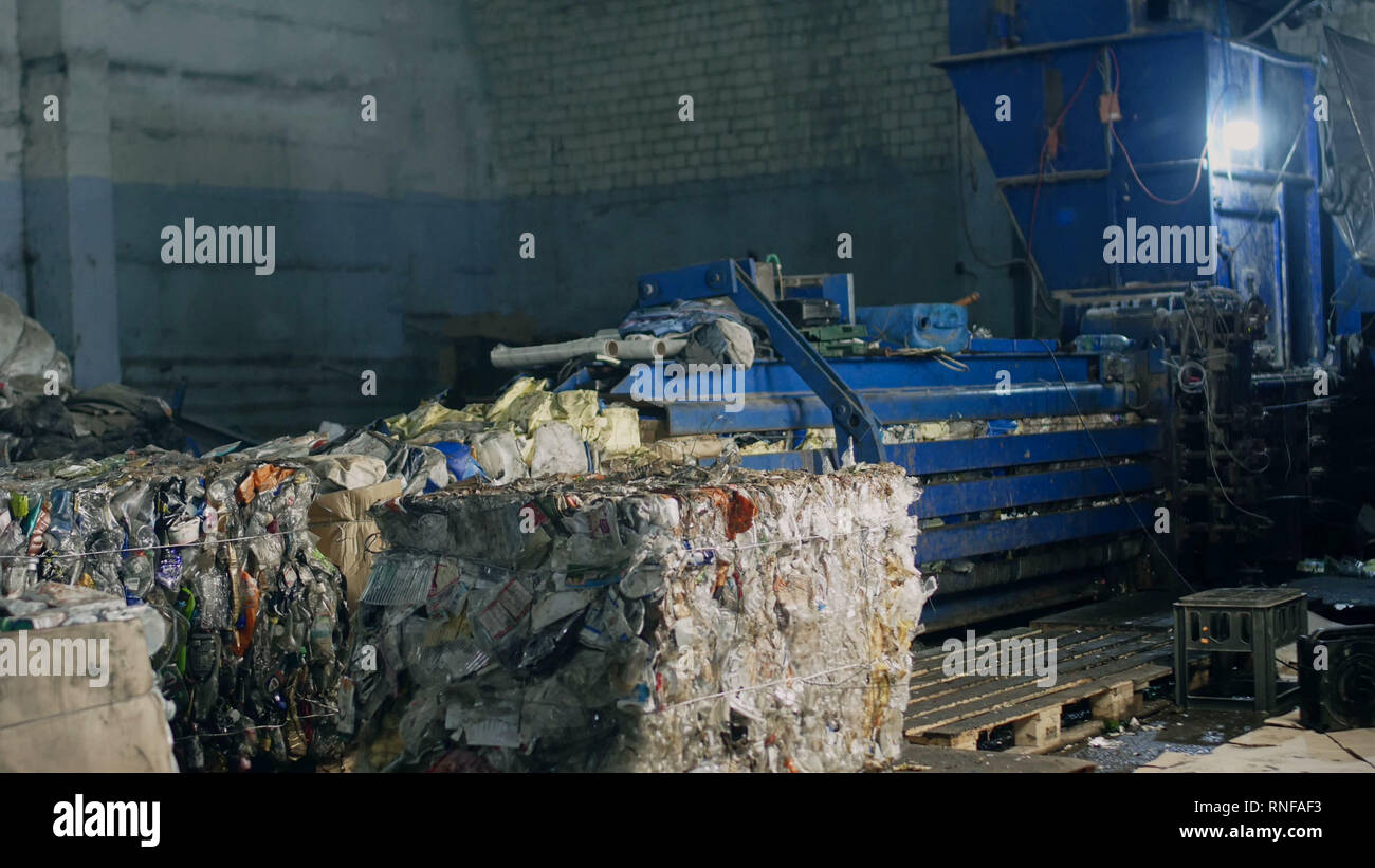 Press at waste recycling plant for pressing plastic and cardboard waste ...