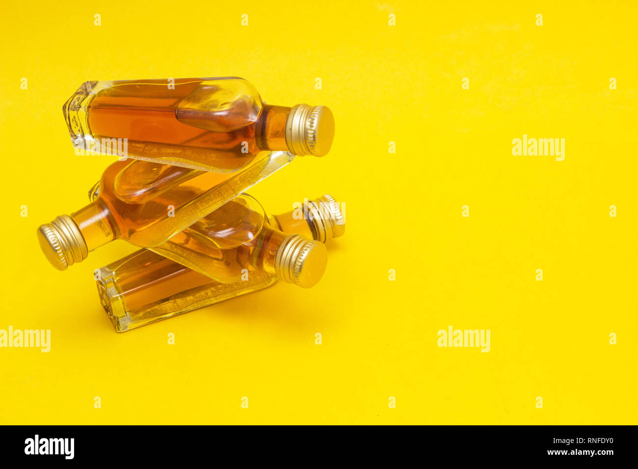 Small bottles with alcohol on a yellow background, close-up, copy space ...