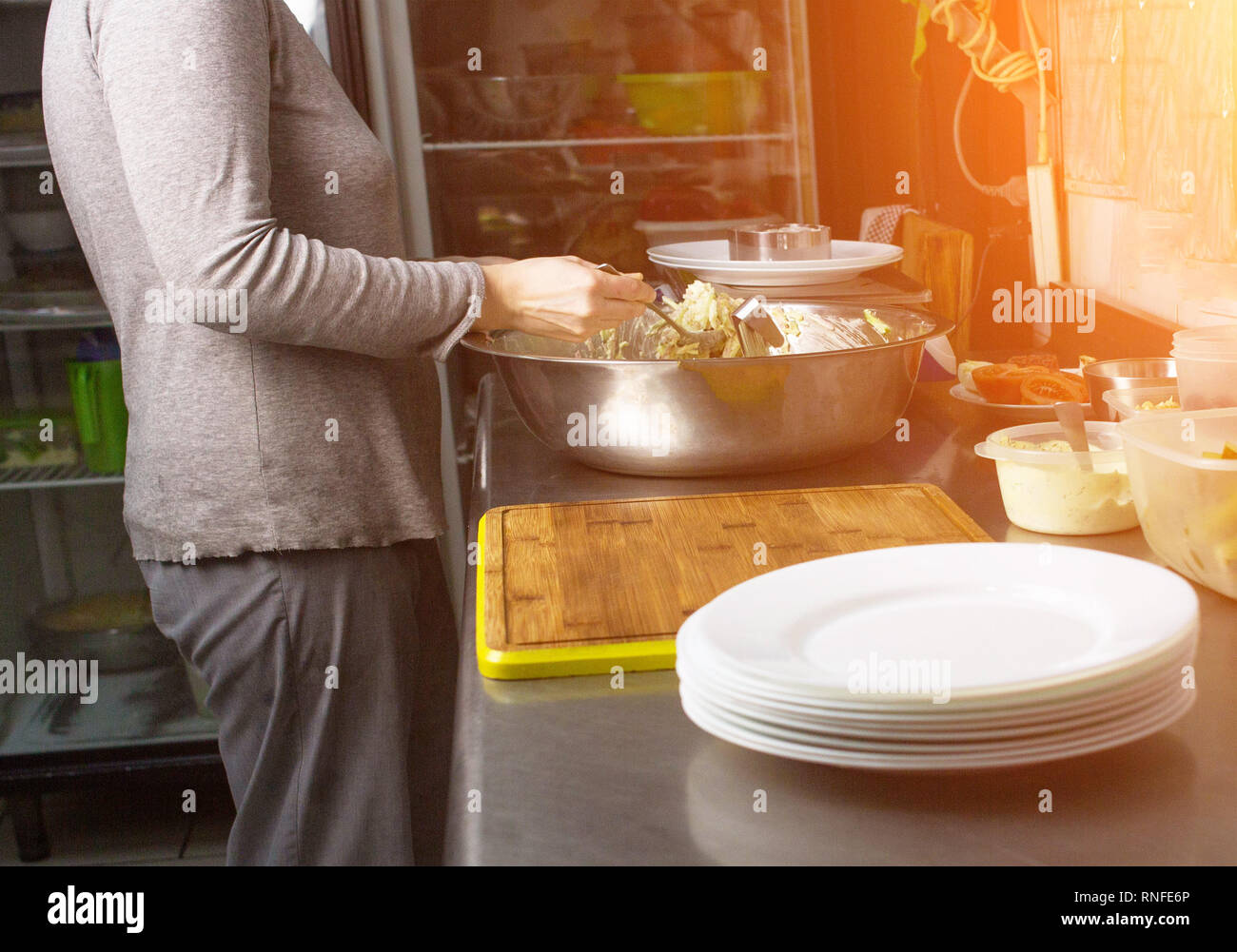A cook in the kitchen weighs portions of salad on scales in grams and ...