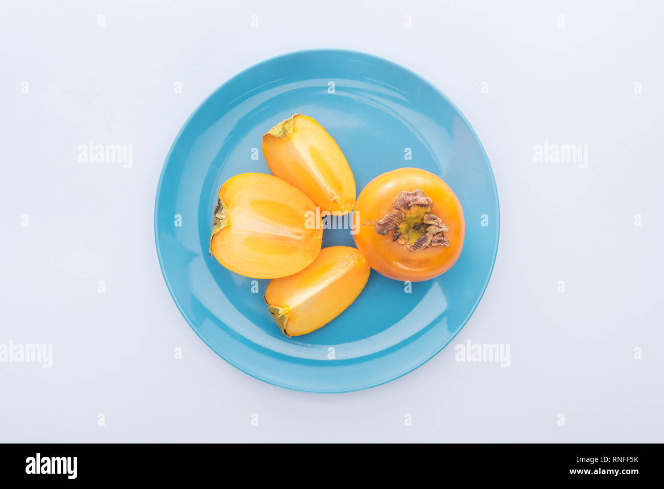 top view of sweet cut and whole persimmons on blue glass plate Stock ...