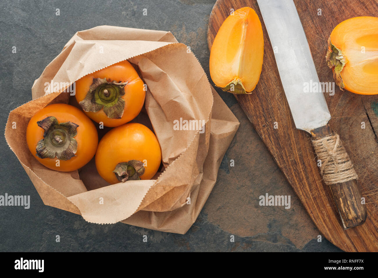 top view of whole persimmons in paper packet and sliced on cutting ...