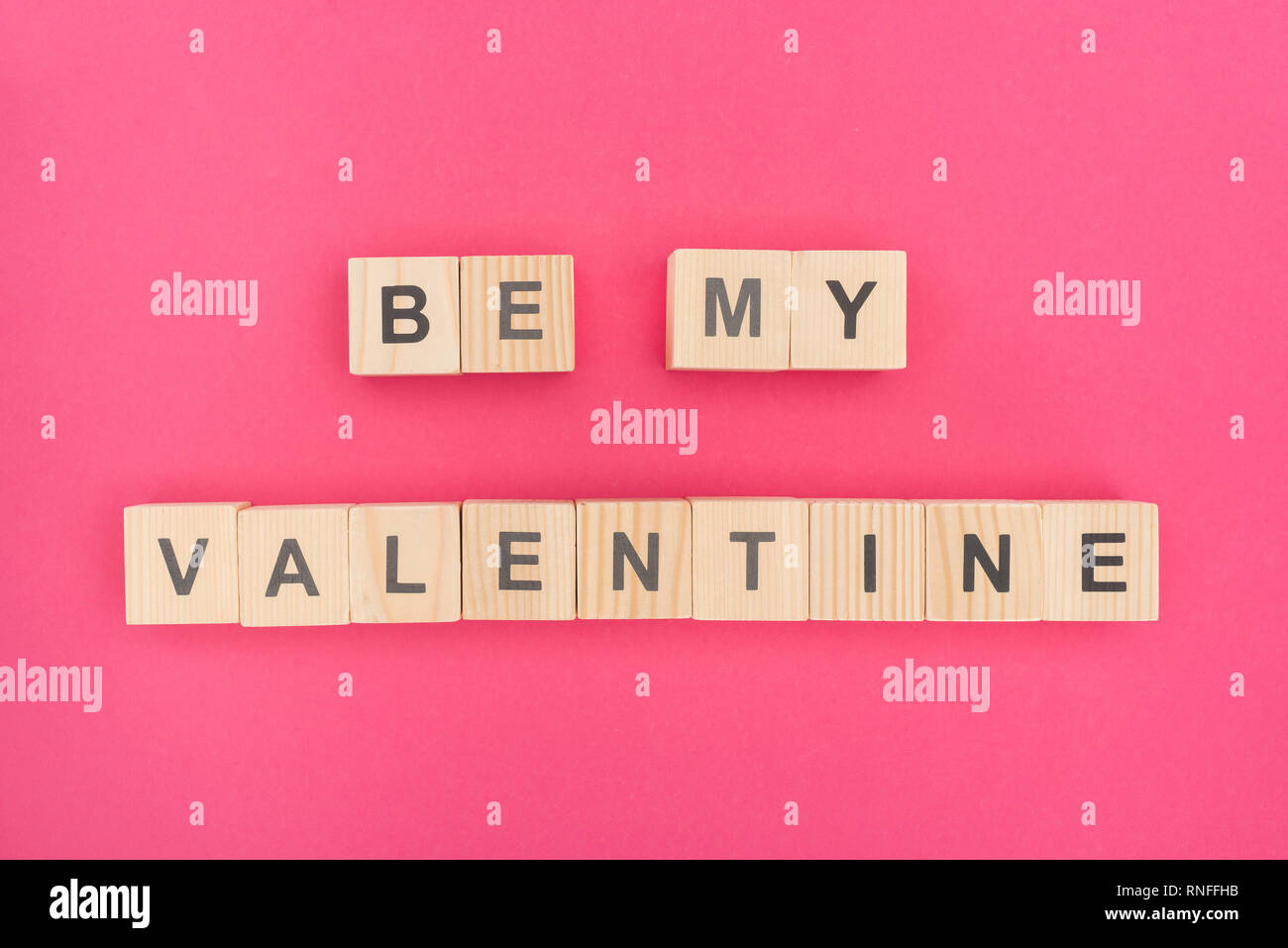 top view of be my valentine lettering made of wooden cubes on pink ...