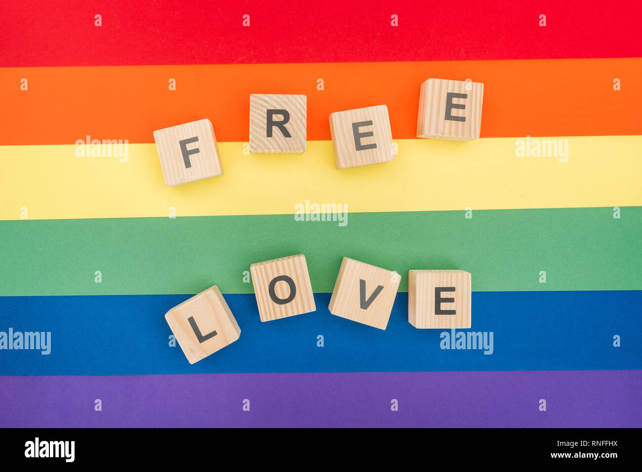 top view of free love lettering made of wooden cubes on paper rainbow ...