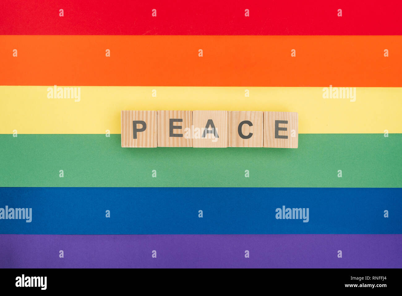 top view of pease lettering peace made of wooden cubes on paper rainbow ...