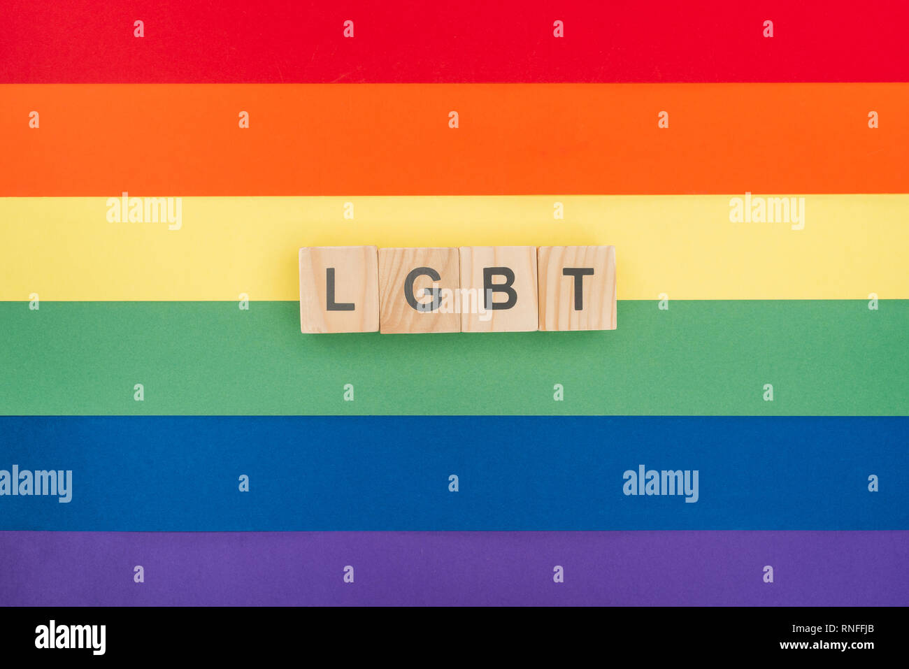 top view of lgbt lettering made of wooden blocks on paper rainbow ...